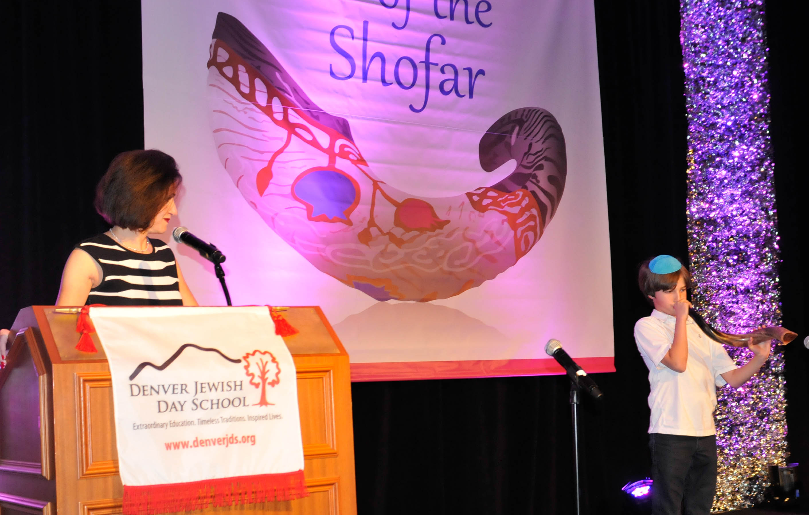 Noah Williamson on stage with emcee, Board Chair Lisa Reckler Cohn