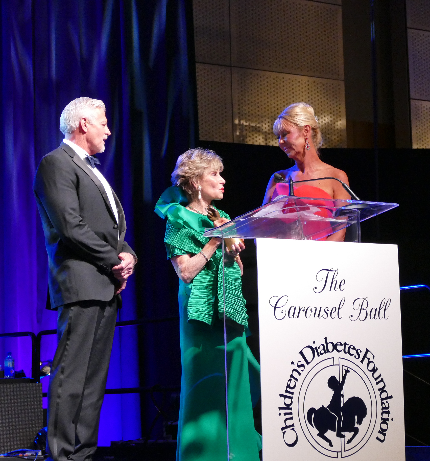 Honorees Tom and Lisa Corley on stage with Arlene Hirschfeld, center